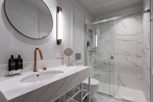 Uma casa de banho moderna com duas lavatórios, um espelho grande e uma cabine de duche de vidro.