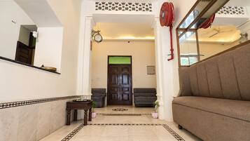Sala de estar com sofá, mesa de centro e lareira. Há uma porta que dá para outro quarto e uma janela com vista.