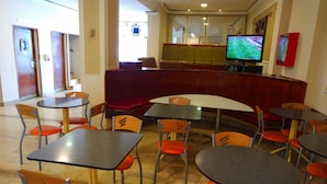 Uma área de refeições com mesas, cadeiras, uma televisão e um balcão.