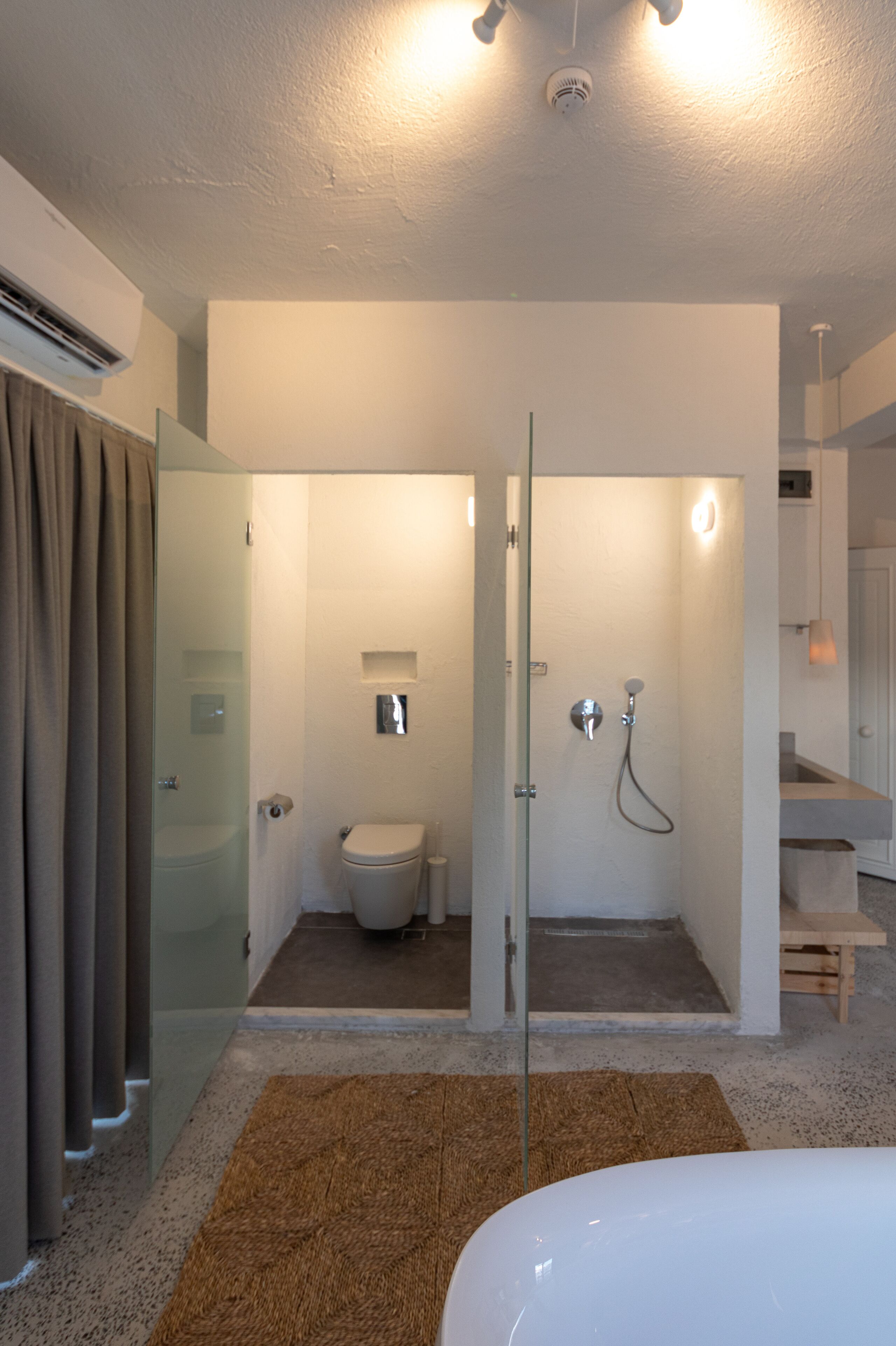 Uma casa de banho moderna com cabine de duche em vidro, sanita e banheira.