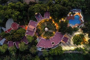 Vista aérea de um resort com um pátio circular central, edifícios ao redor e uma piscina.