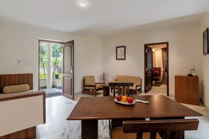 Uma sala de jantar moderna com uma mesa de madeira, dois sofás bege e um armário de madeira.