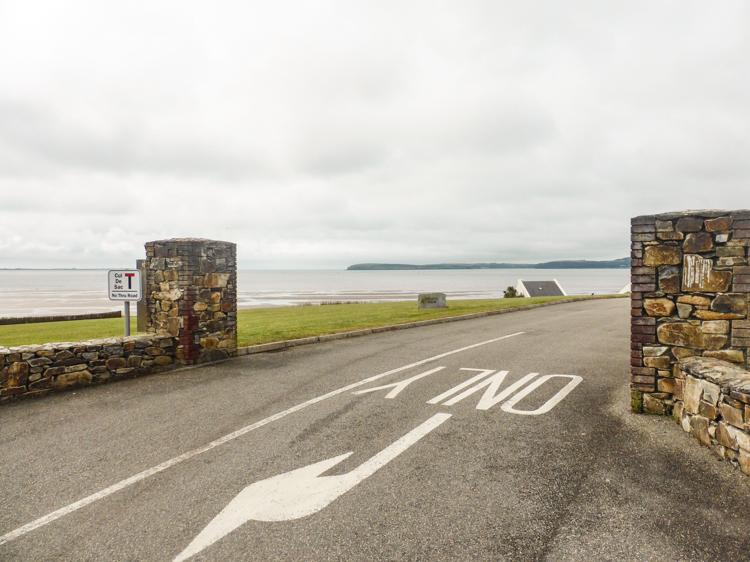 Uma estrada com uma placa de 'Proibido o Sentido' e vista para o mar.