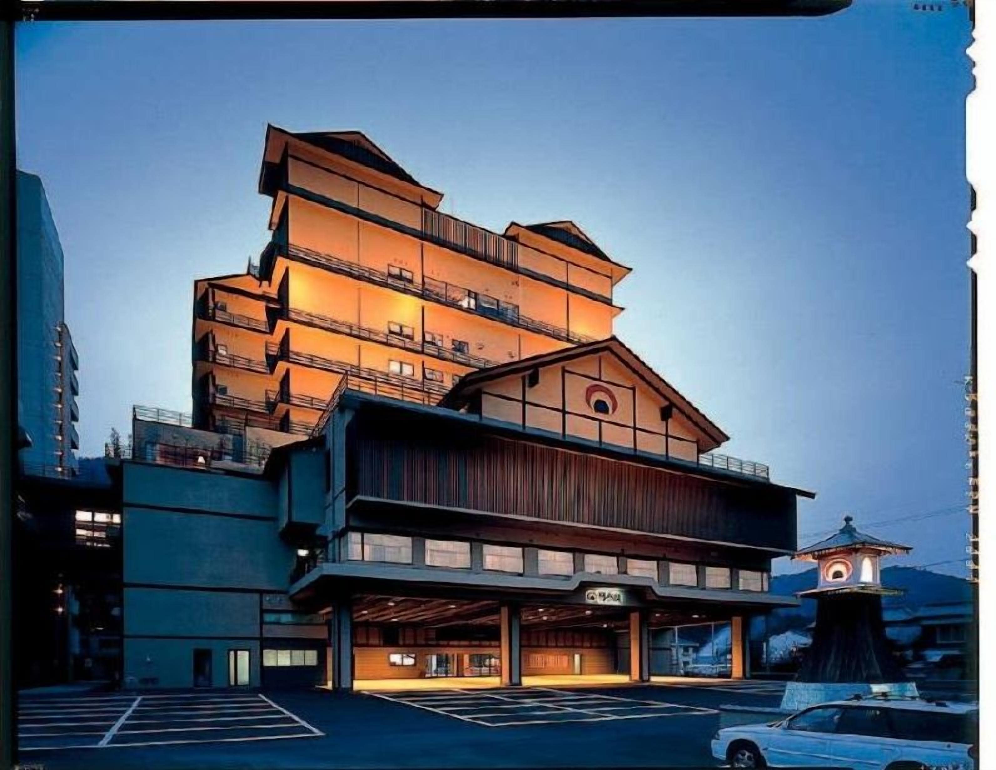 Um edifício com vários andares, teto plano, área de estacionamento coberta e uma pequena estrutura em forma de torre.