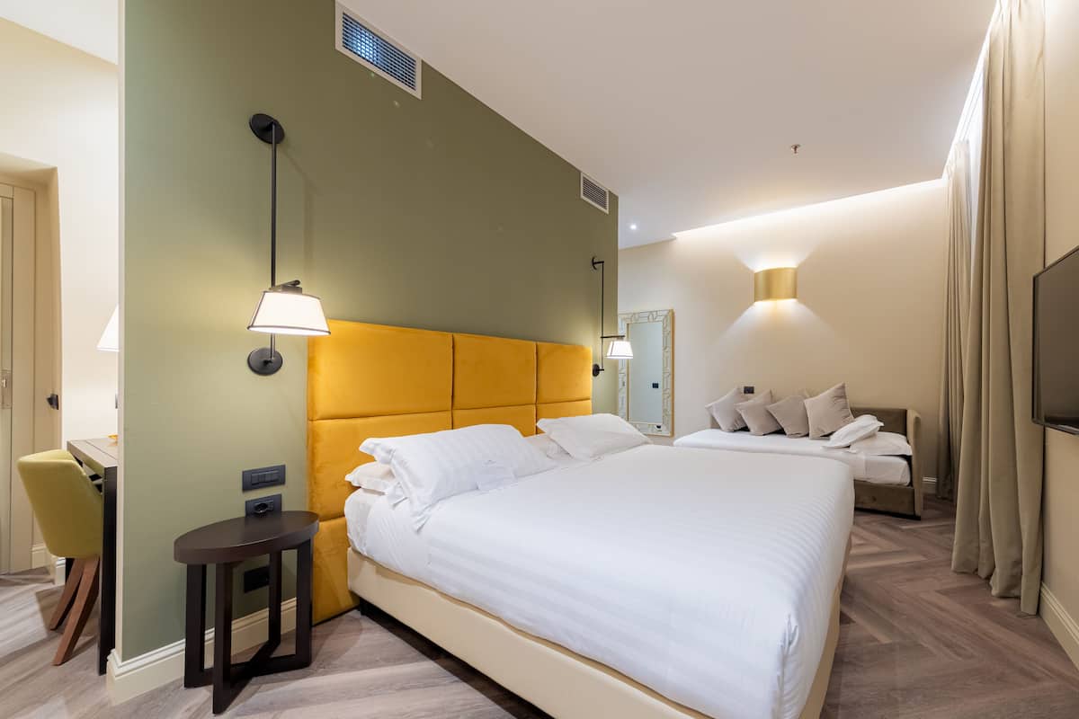 Quarto de hotel com duas camas, uma escrivaninha e uma cadeira.