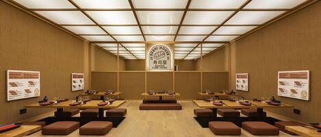 Um restaurante de sushi com área de estar central, cabines e mesas.