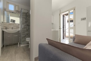 Casa de banho moderna com chuveiro, sanita e lavatório.