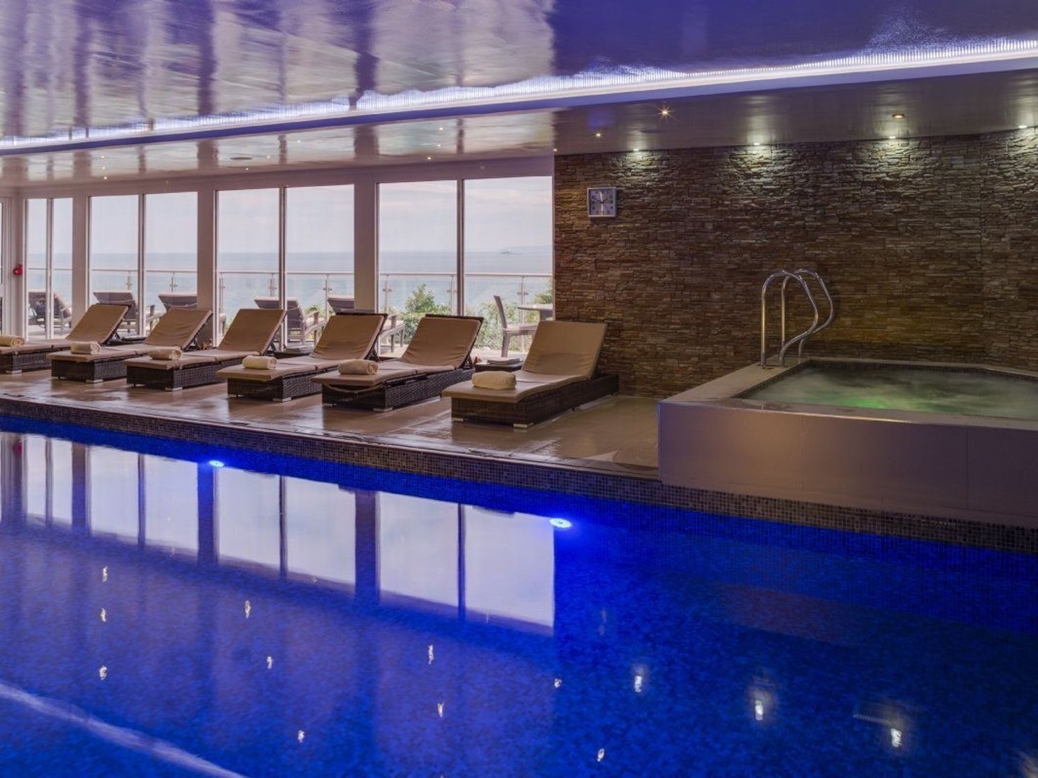 Uma área de piscina com espreguiçadeiras e uma banheira de hidromassagem.