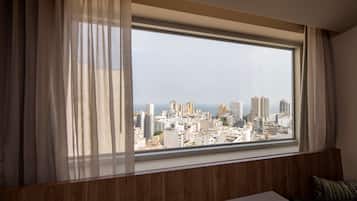 Quarto de hotel com uma grande janela vista para a paisagem urbana.