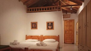 Quarto com duas camas de madeira, um guarda-roupa de madeira e uma porta que dá para outro espaço.