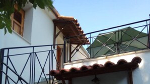 Um edifício com porta de madeira, varanda com toldo verde e escadaria com grades de metal.