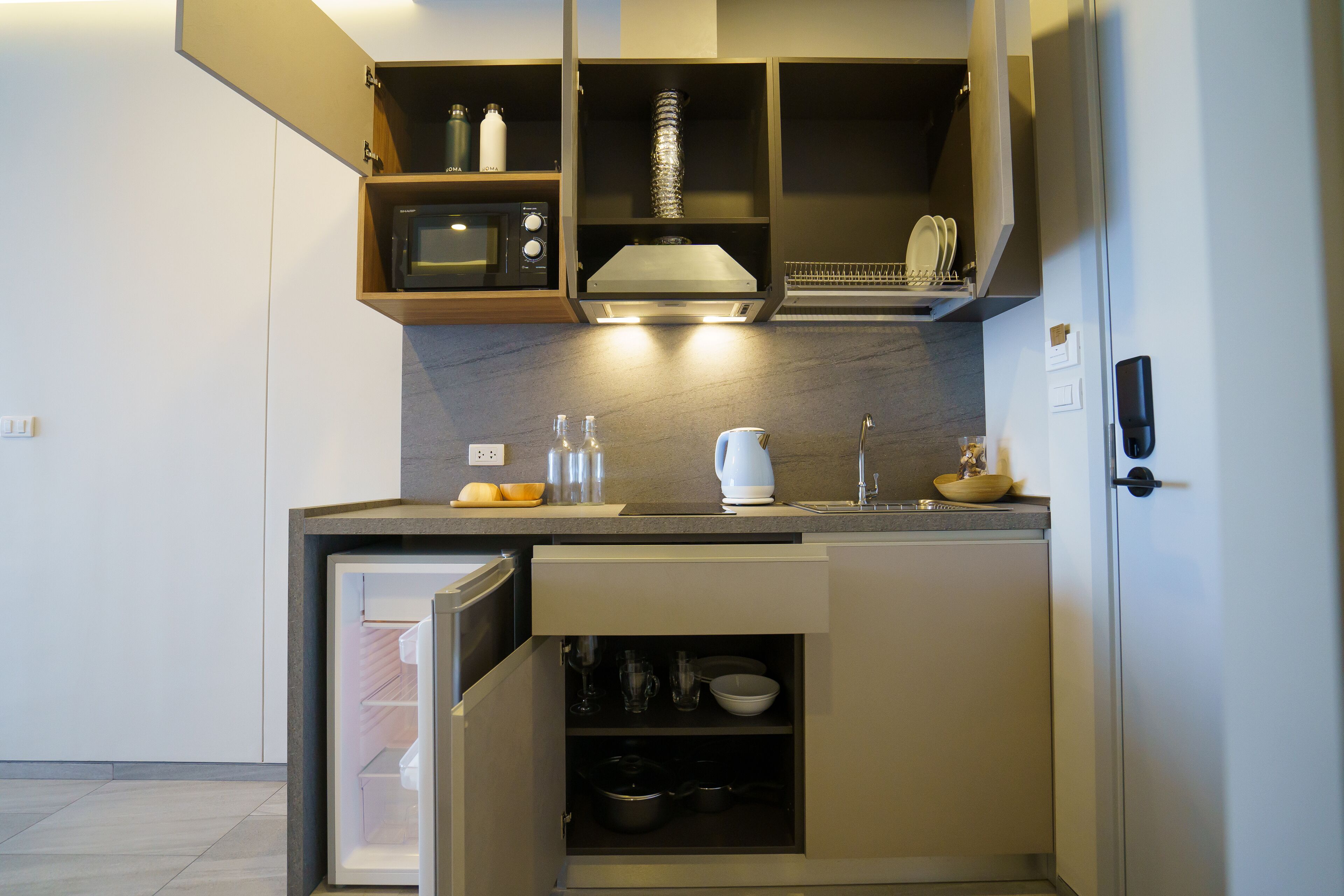 Uma cozinha compacta com eletrodomésticos embutidos, micro-ondas e escorredor de louça.