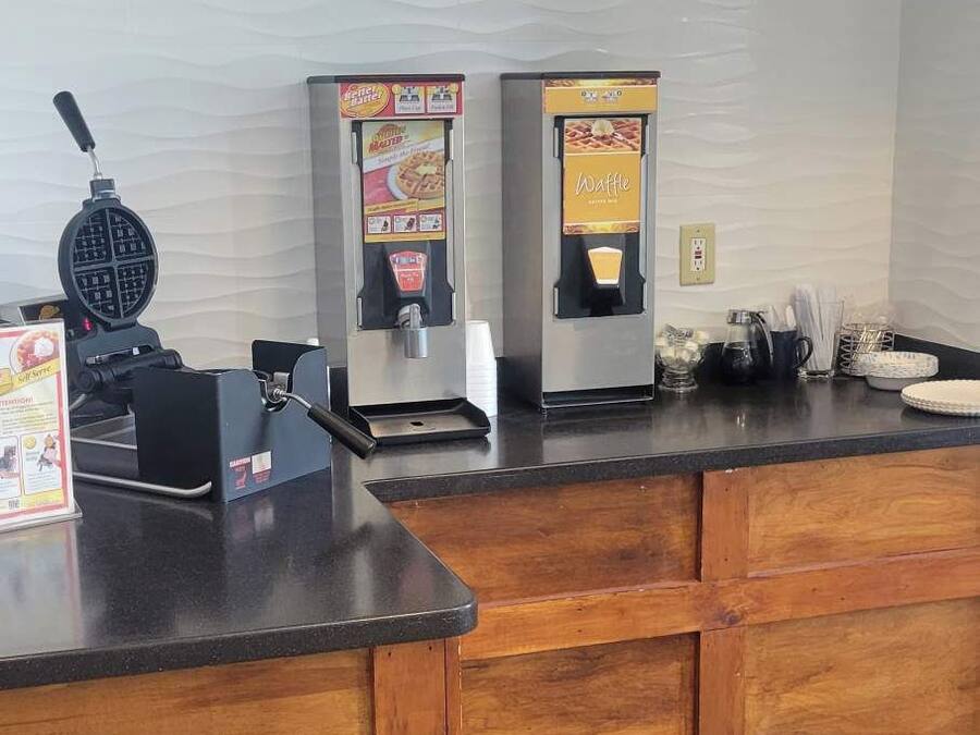 Bancada com máquina de waffles, dois dispensadores de waffles e uma máquina de café.