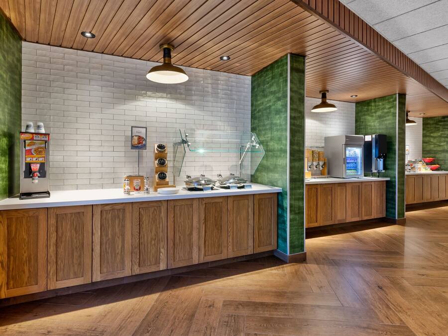 Uma cozinha moderna com armários de madeira, bancada branca e parede verde decorativa.