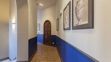 Um corredor com porta de madeira, obras de arte emolduradas nas paredes e esquema de cores azul e branco.