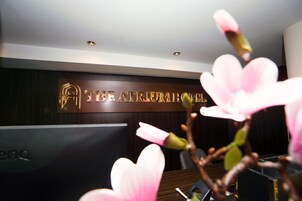 Uma receção com uma placa a indicar "THE ATRIUM HOTEL" e um design de interiores moderno.
