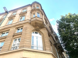 Canto de um edifício com arquitetura clássica, destacando uma janela em arco e detalhes em pedra decorativa.