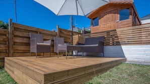 Um deck de madeira com móveis de vime e um grande guarda-sol.