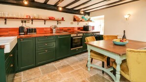 Uma cozinha com armários verdes, uma mesa de madeira e chão de azulejos.