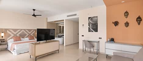 Quarto de hotel moderno com cama, televisão, sofá e área de jantar.