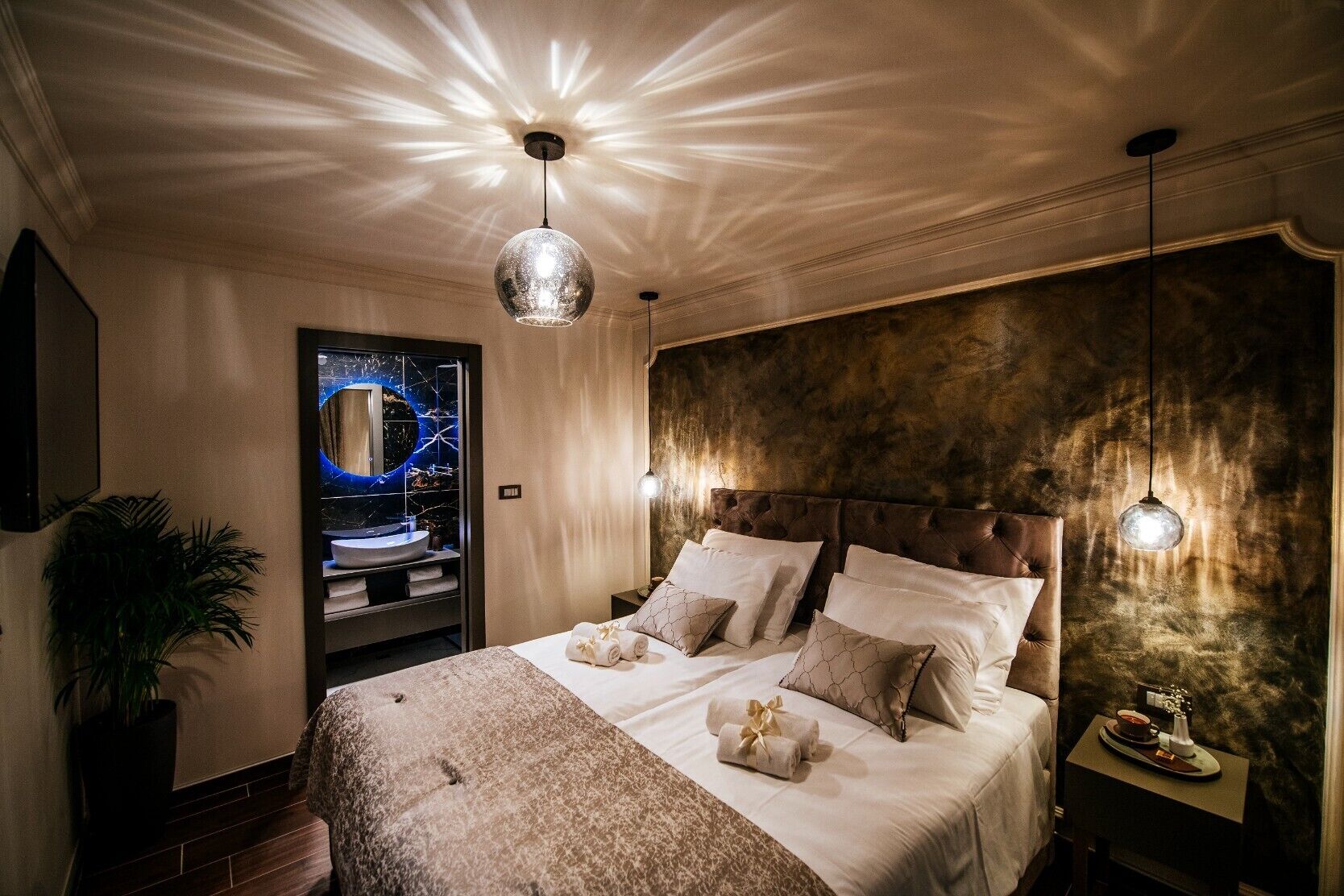 Um quarto espaçoso com uma cama grande, um lavatório de mármore e um candelabro moderno.