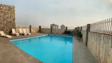 Piscina com espreguiçadeiras e um muro de pedra.