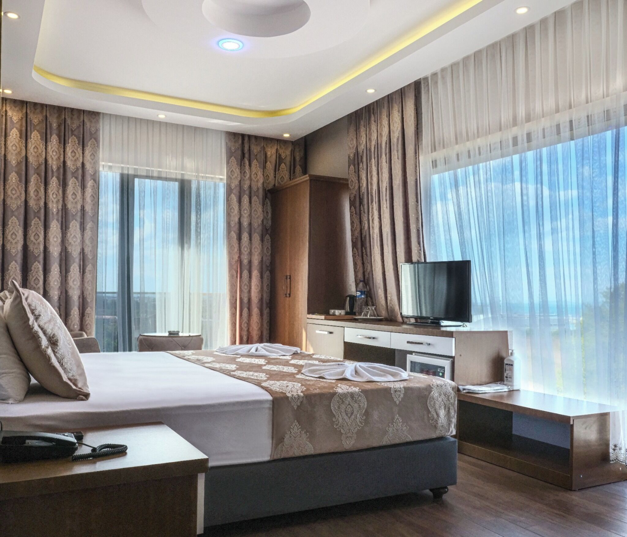 Quarto de hotel com uma cama grande, uma escrivaninha, uma televisão e vista para o exterior.