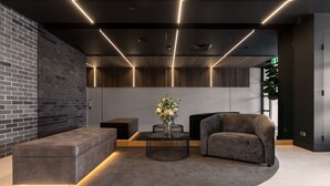 Um lobby moderno com um sofá, uma mesa redonda com um vaso e uma parede de tijolos.