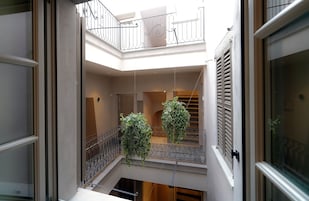 Um interior em vários níveis com varanda, escada e plantas penduradas.