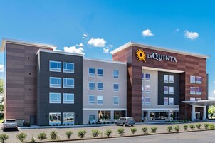 Um hotel moderno com a placa 'Quinta', apresentando uma estrutura de vários andares com uma combinação de estilos de janelas e uma entrada coberta.
