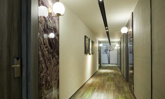 Um corredor com paredes de mármore, obras de arte emolduradas e iluminação embutida.