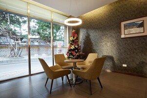 Um interior moderno com uma mesa redonda e quatro cadeiras, um pinheiro de Natal decorado e janelas amplas com vista para o exterior.