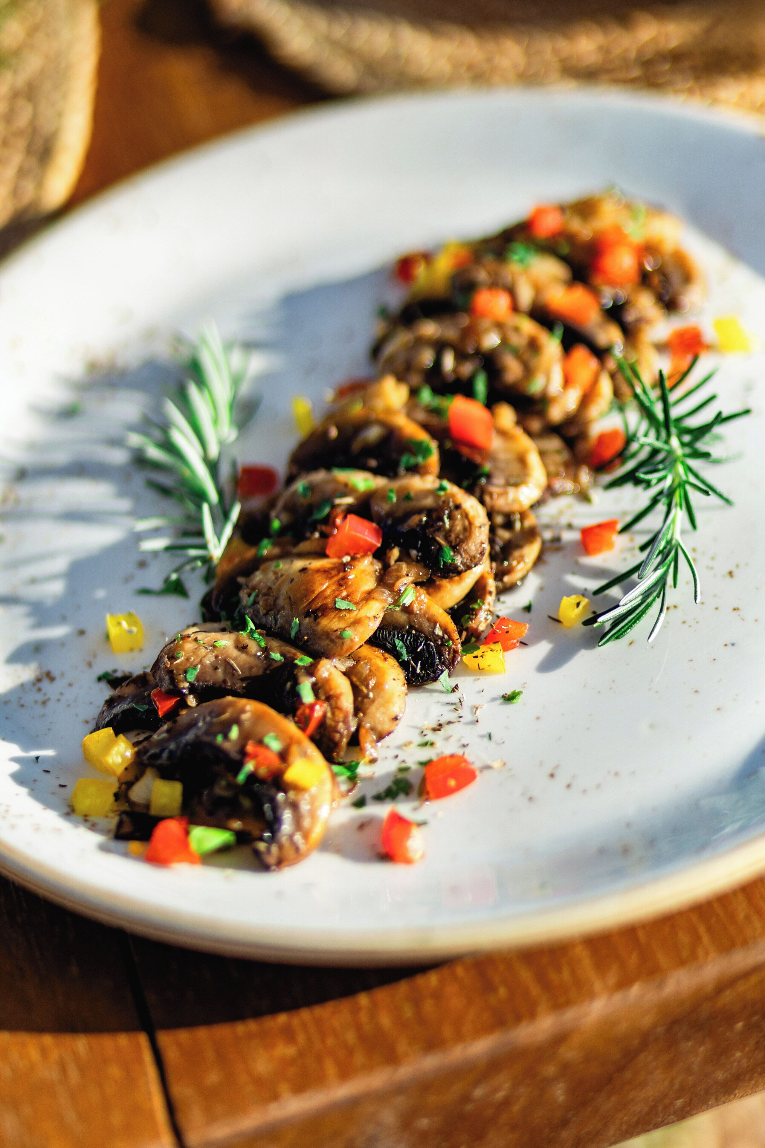 Um prato branco com um guisado de cogumelos fatiados e legumes picados, decorado com ervas.