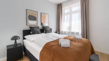 Quarto moderno com cama, mesa de cabeceira e uma obra de arte na parede.