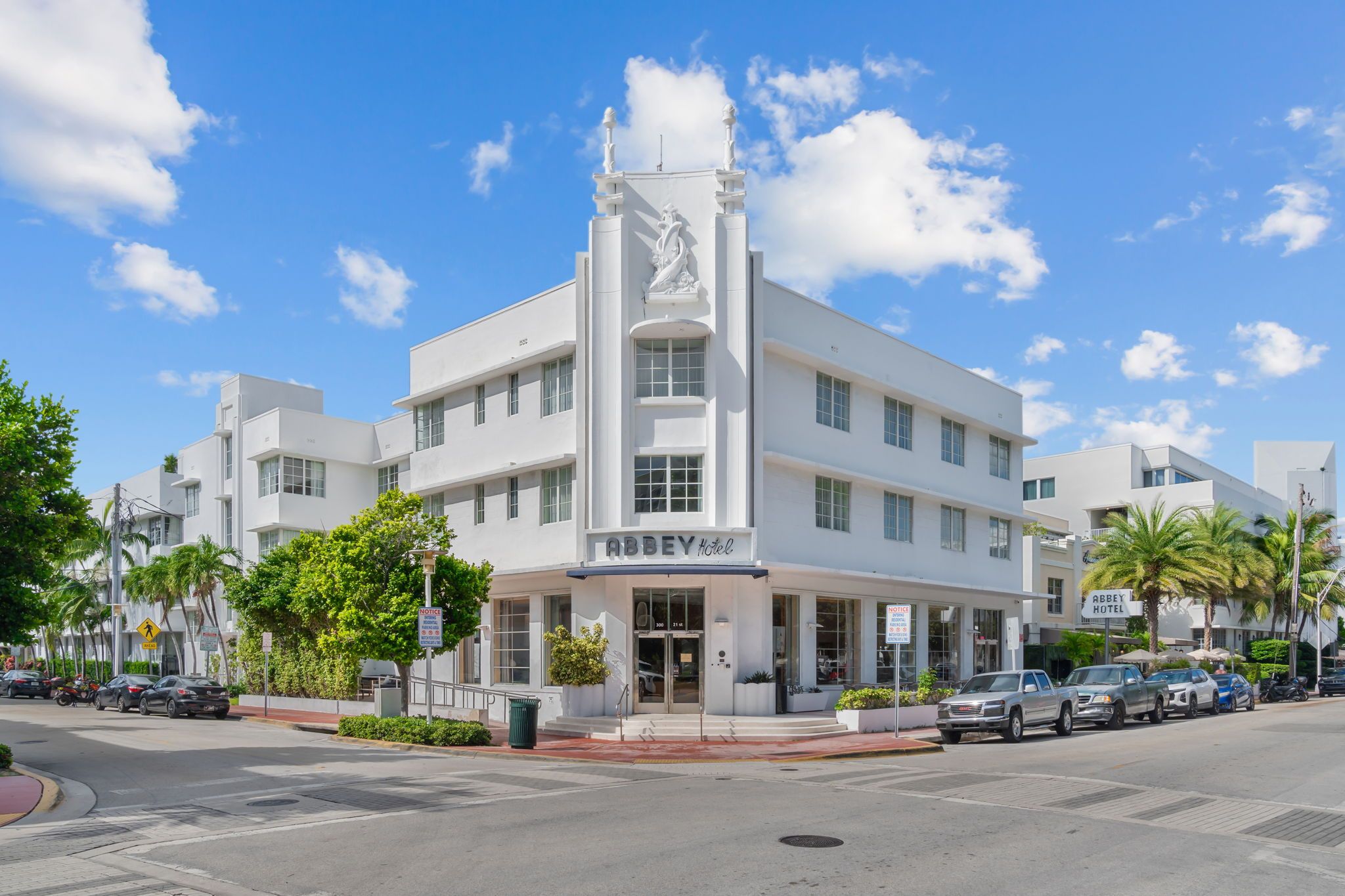 Hotel branco de vários andares, com entrada notável e uma estátua na fachada.