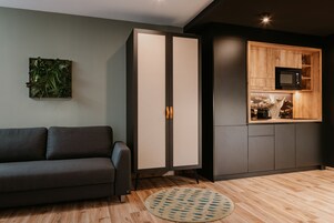 Uma sala de estar moderna com um sofá escuro, um armário com micro-ondas e um objeto decorativo na parede.