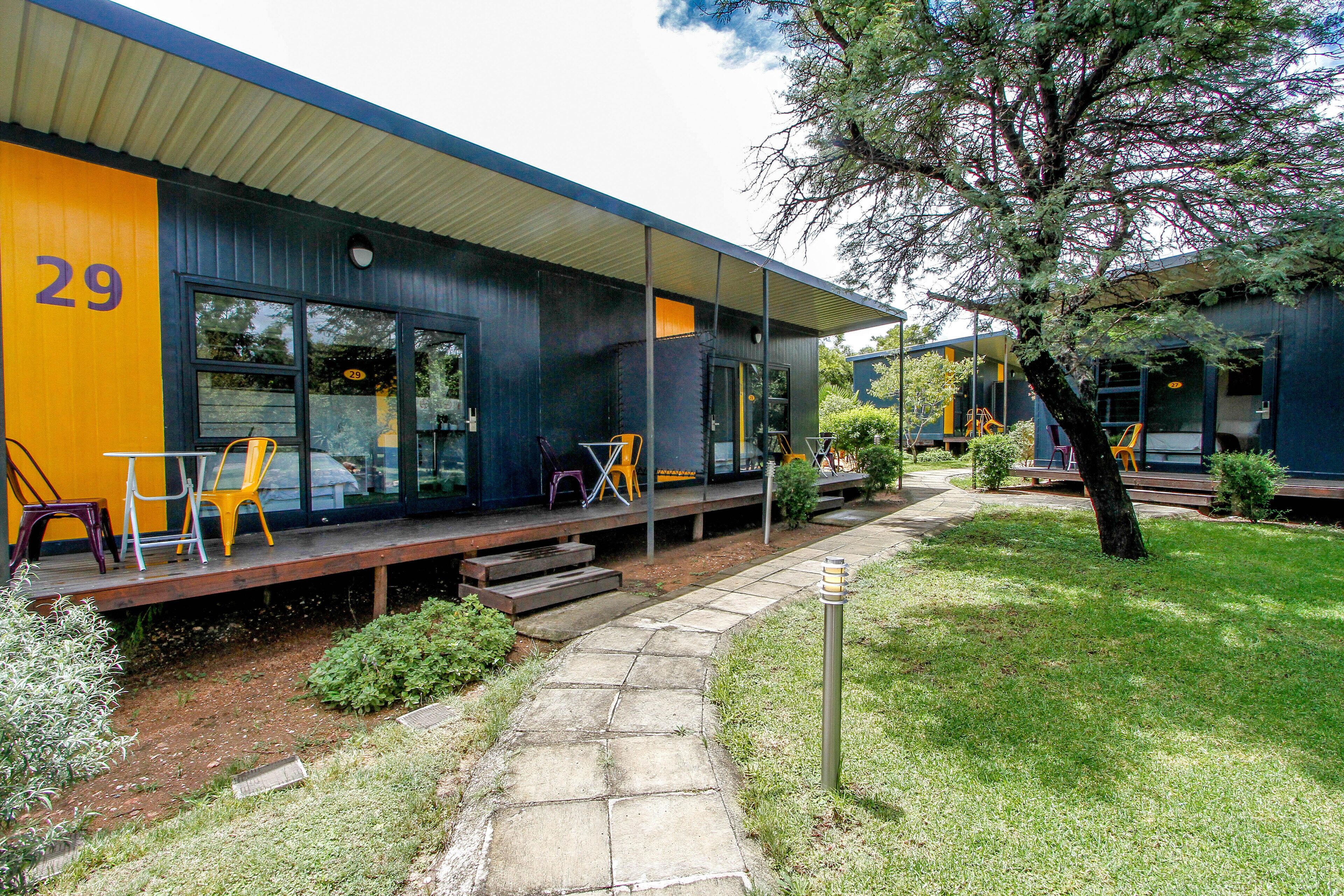Um edifício moderno com o número '29' na fachada, área externa com cadeiras e um jardim bem cuidado.