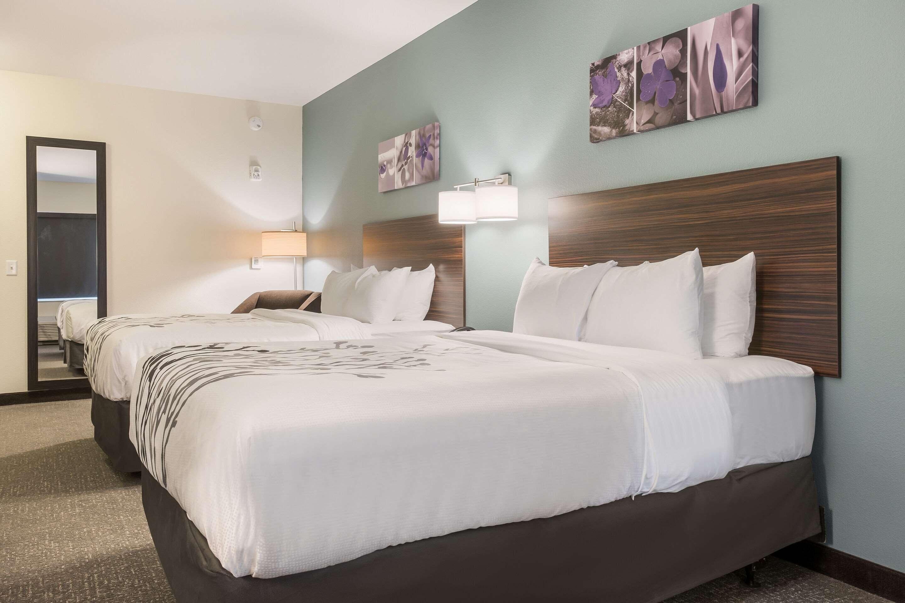 Quarto de hotel com duas camas, um espelho grande e obras de arte nas paredes.