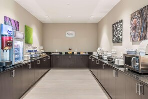 Uma cozinha moderna com uma ilha central, equipada com diversos eletrodomésticos e uma máquina de café.