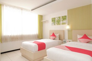 Quarto de hotel com duas camas, uma janela grande com cortinas e uma obra de arte na parede.