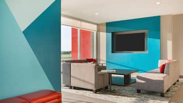 Uma sala de estar moderna com uma televisão grande, assentos confortáveis e vista para o exterior.