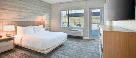 Quarto de hotel com cama, televisão de tela plana, janela com vista e ar condicionado fixado na parede.
