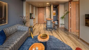 Uma sala de estar moderna com sofá, mesa de centro e um espaço de jantar com banquetas.