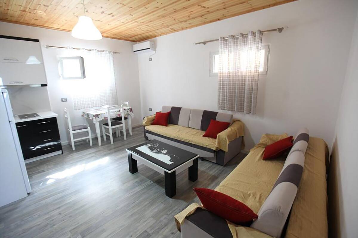 Uma sala de estar moderna com sofá, mesa de centro e área de jantar com mesa e cadeiras.