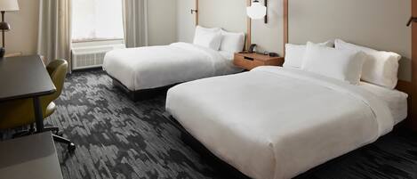 Quarto de hotel com duas camas, uma escrivaninha, uma cadeira e uma janela grande com cortinas.