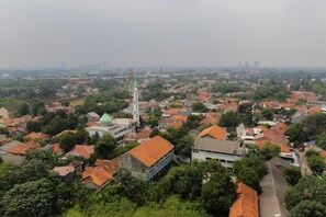 Vista aérea de uma cidade com uma igreja imponente, com uma cúpula verde e um campanário alto, cercada por edifícios residenciais com telhados de telhas vermelhas.