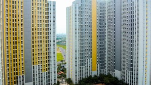 Um edifício residencial alto com várias varandas e vista para uma estrada e áreas verdes.