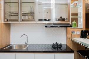 Uma cozinha moderna com pia de aço inoxidável, fogão a gás e armários com portas de vidro.