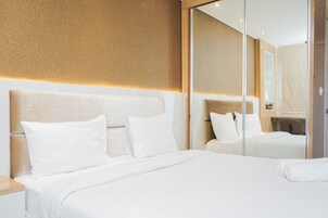 Quarto de hotel moderno com uma cama grande, uma mesinha de cabeceira e um espelho refletindo o quarto.