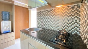 Cozinha moderna com bancada preta, fogão a gás, dispensador de água e painel de fundo xadrez.